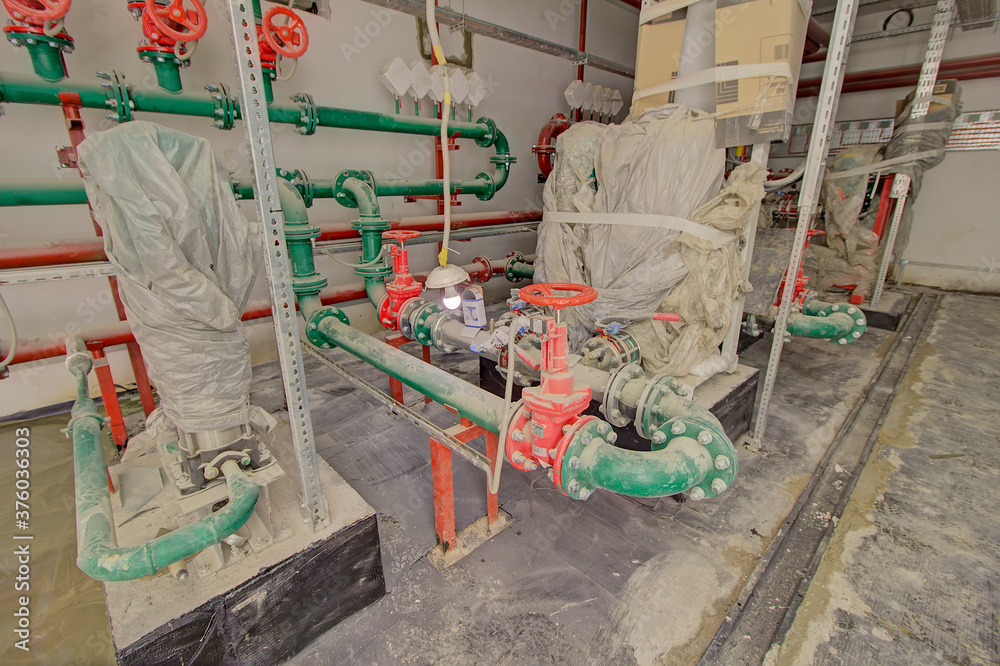 Mounting red and green piping. Installation of fittings in basement of ...