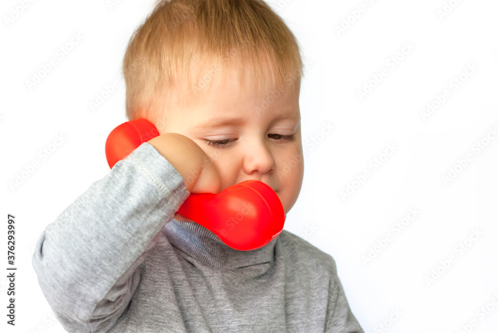 Portrait of an astonished cute little boy holding a red telephone ...