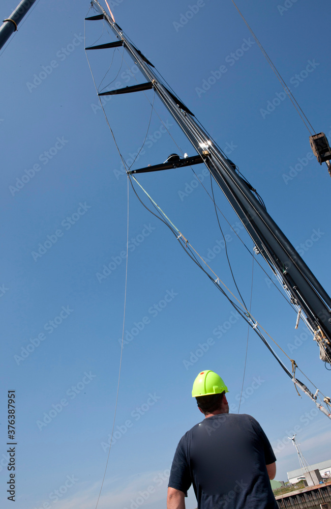 Placing the mast with a crane. Rigging. Ship building industry ...