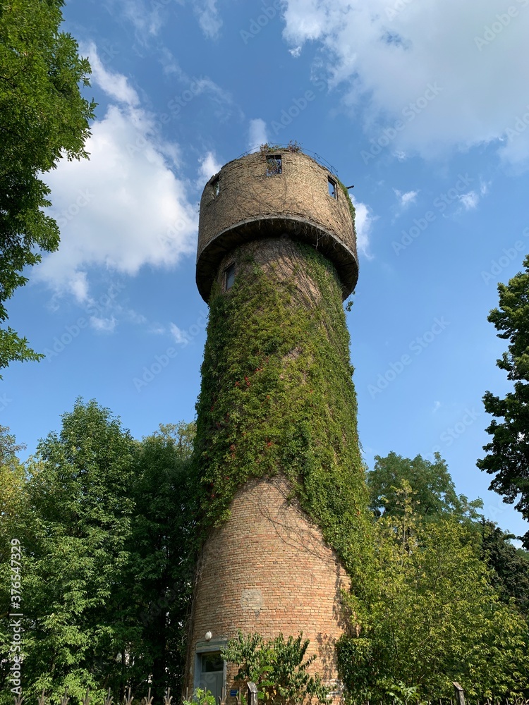 Water tower against the blue sky. The old fortress tower in the forest ...