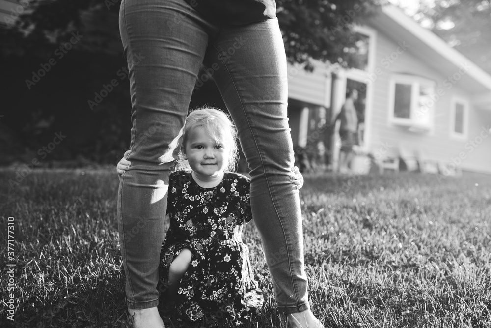 little girl peeks through moms legs outside Stock Photo | Adobe Stock