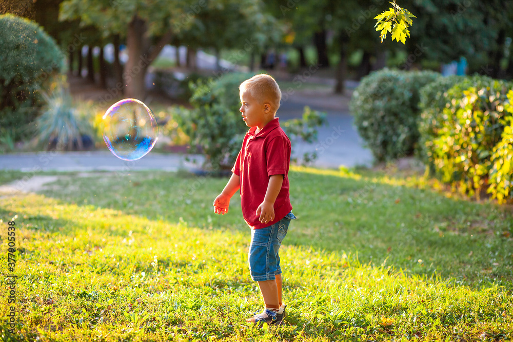 Little cute boy with Down Syndrome plays with huge soap bubbles in the ...