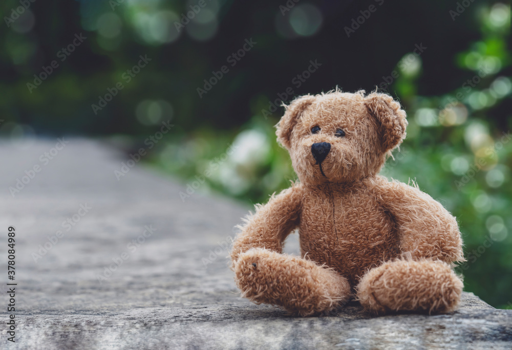 Teddy bear with sad face sitting on footpath blurry background ...
