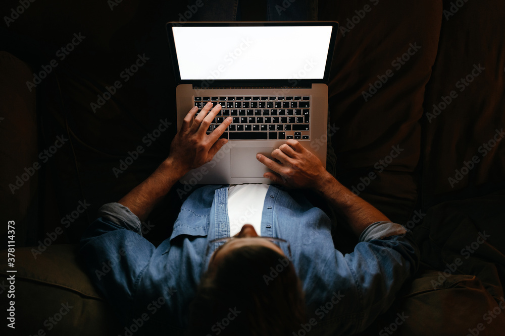 Young businessman in eyeglasses is working remotely from home late at ...