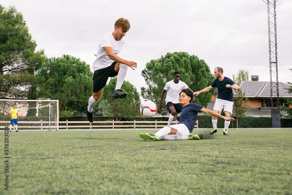 Soccer player avoids incoming slide tackle during a soccer match Stock ...
