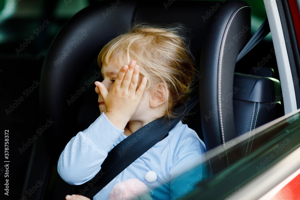 Sad upset little kid girl sitting in car in traffic jam during going ...