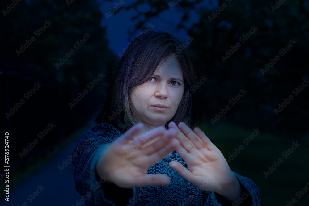 A frightened young girl tries to protect herself by stretching her arms ...