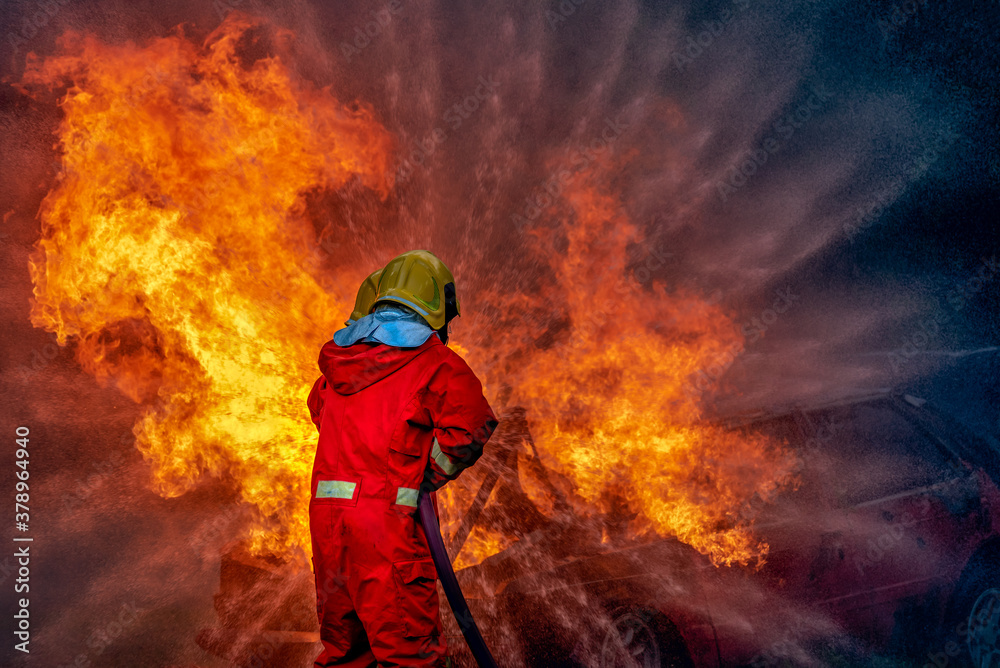Firemen fighting raging fire with huge flames of burning and fuel ...