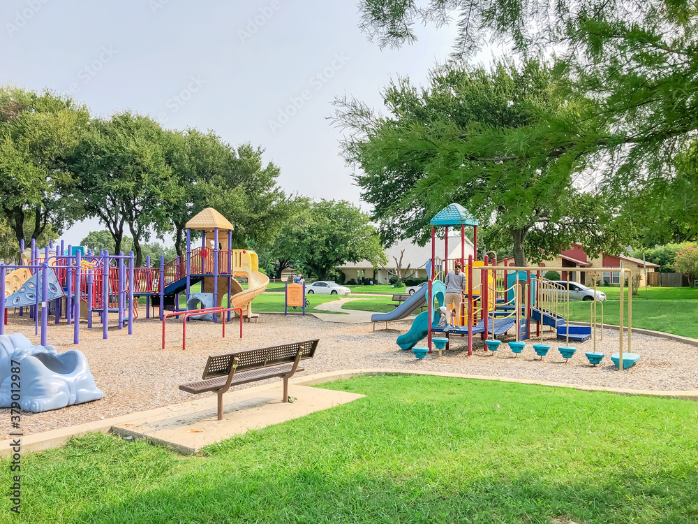 Empty metal bench at colorful playground near residential neighborhood ...