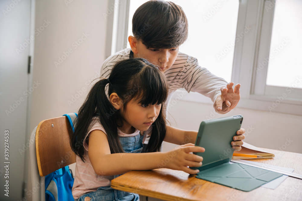 School children using digital tablet device in school classroom ...