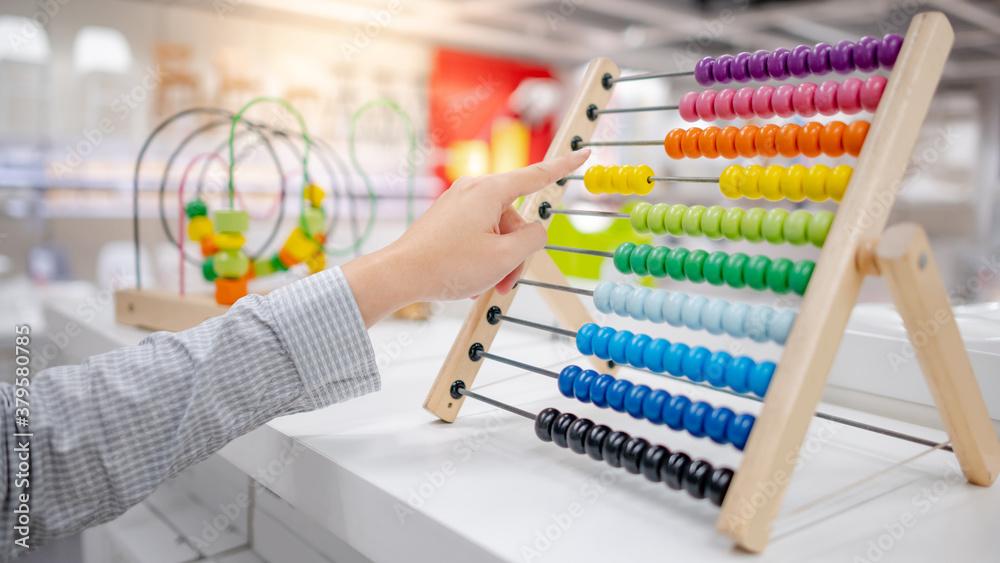 Male hand calculating with beads on wooden rainbow abacus for number ...