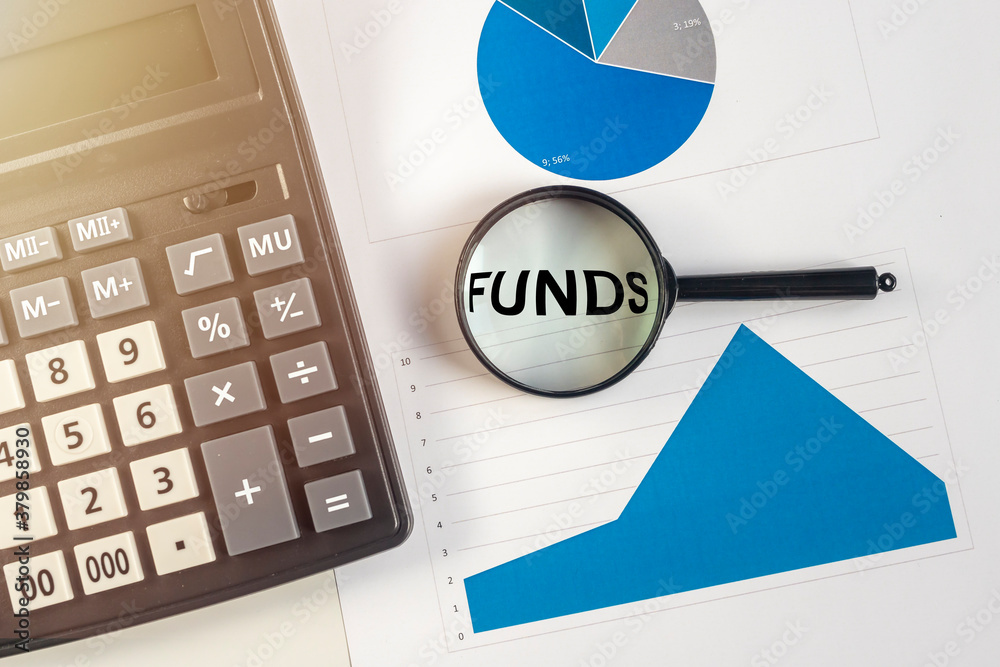 FUNDS Word through magnifying glass on white table with calculator and ...