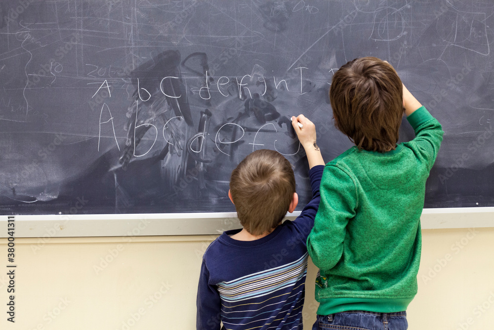 Older brother shows younger brother how to write the alphabet with ...