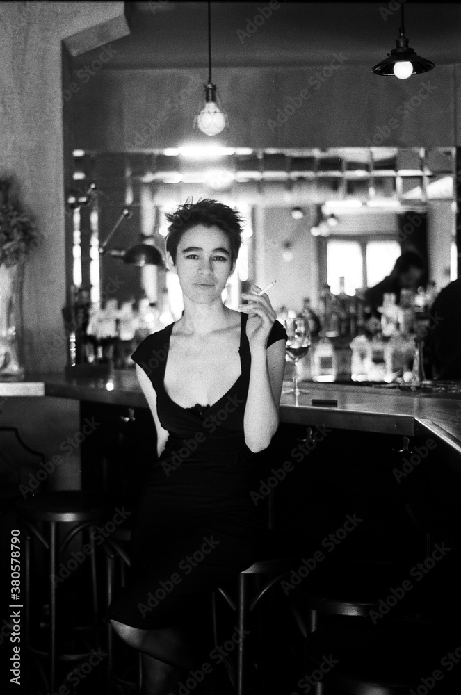 A film portrait of a beautiful young woman smoking cigarette in the bar ...