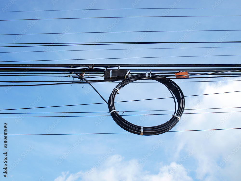 Black fiber optic cable reel hang on wire. Junction box and ...