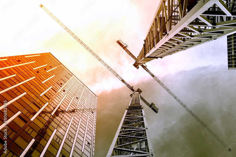 Tower crane. Bottom view of a tall construction cranes next to a modern ...