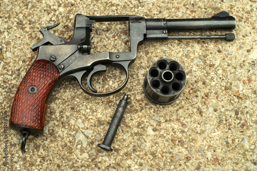 The pistol of the Nagant system is disassembled on the concrete floor ...