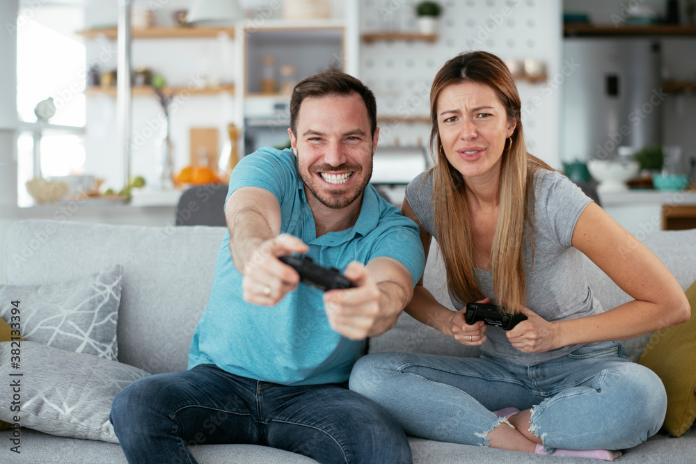 ภาพถ่าย Stock Husband and wife playing video game with joysticks in ...