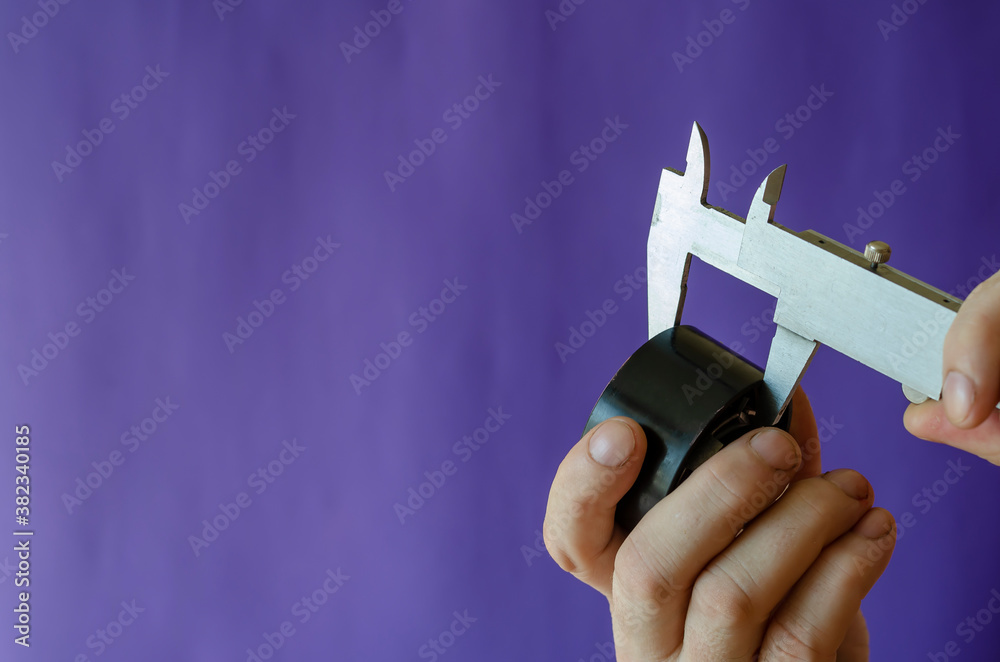 Vernier caliper and timing belt tensioner in hand on blue background ...