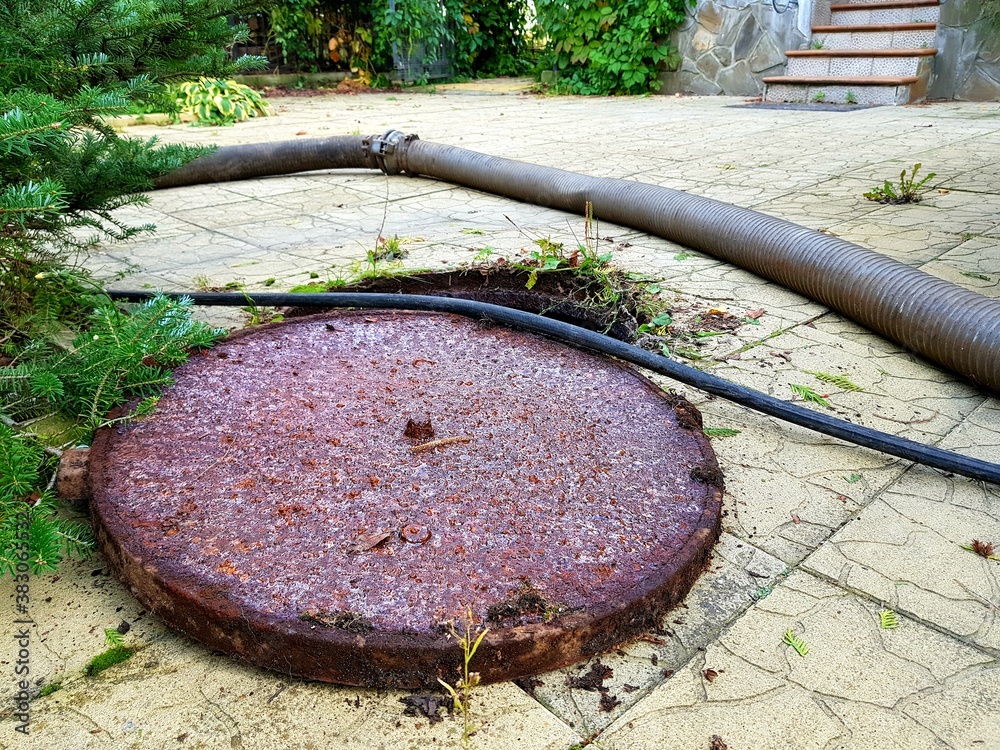 Open sewer manhole. An iron manhole cover is located nearby. Cleaning ...