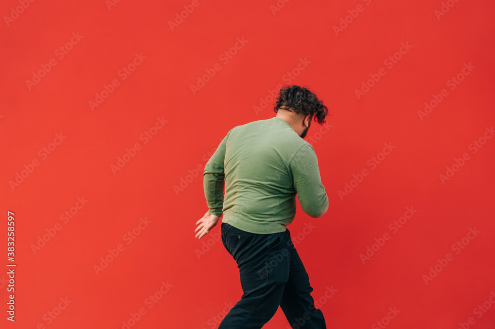Foto de Stock Back of a fat stylish guy dancing hip hop on a red wall ...