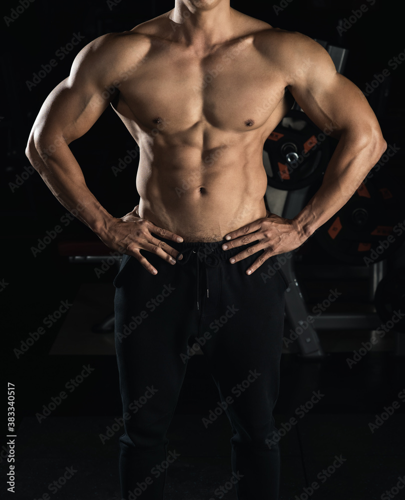Muscular model young man on dark background. Strong brutal guy showing ...