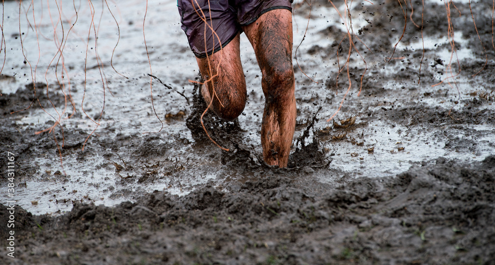 Mud race runner, man running in mud. Runners during extreme obstacle ...