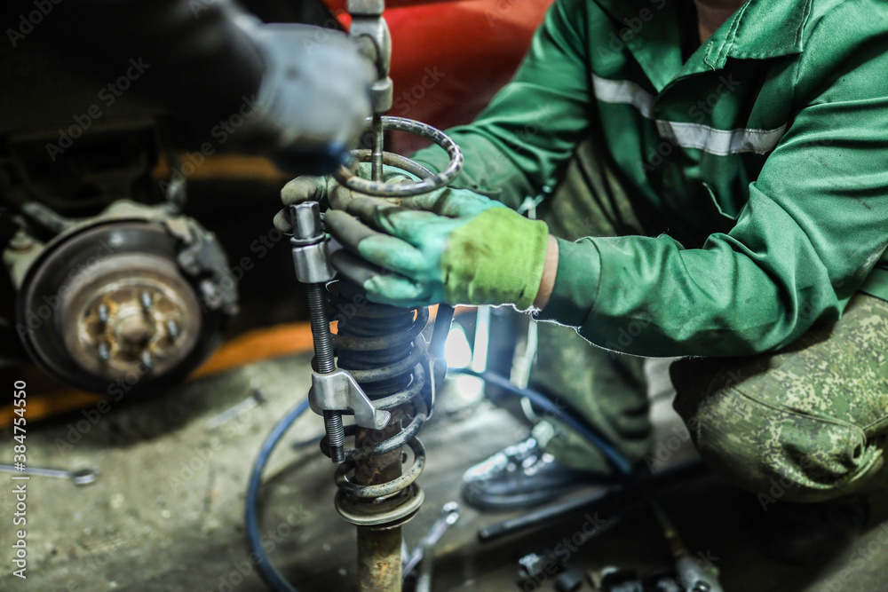 Auto mechanics compress the spring with zip ties to replace the shock ...