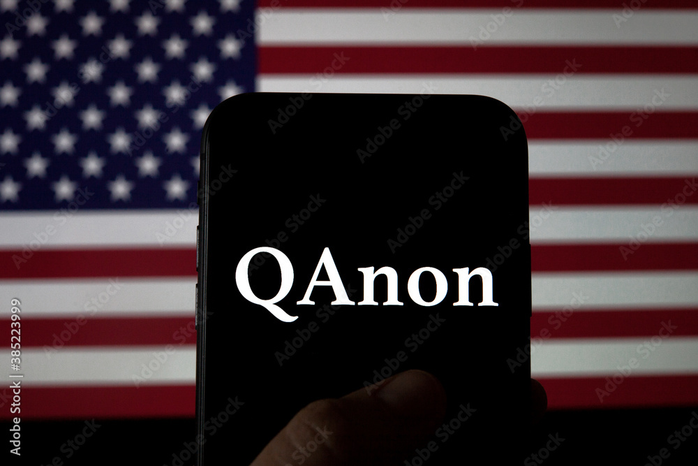 QAnon organisation logo seen on the smartphone which is placed on USA ...