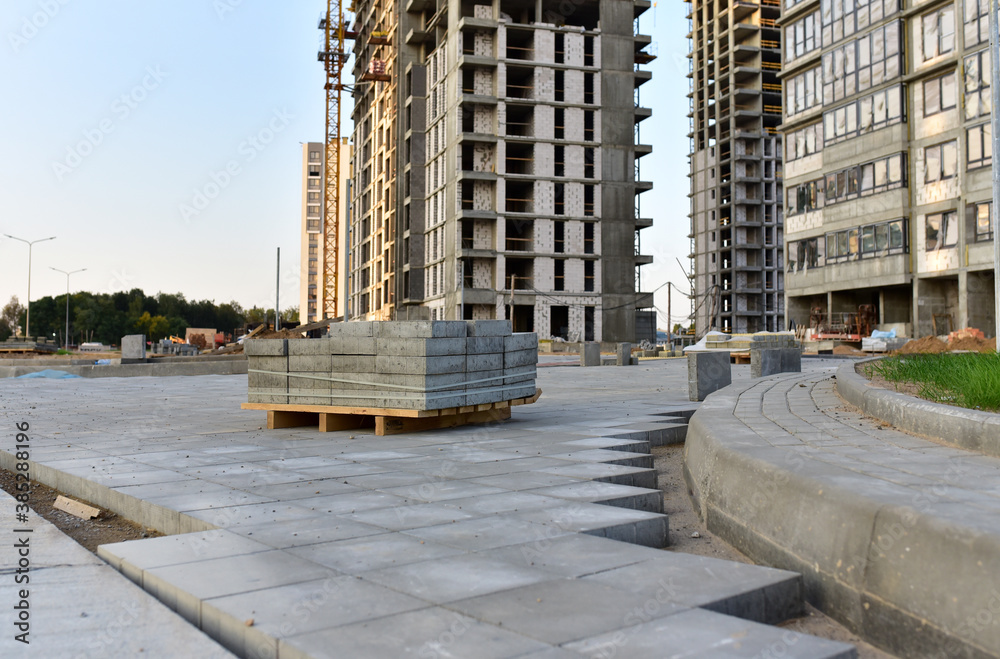 Laying paving slabs in pedestrian zone at construction site. Screeding ...