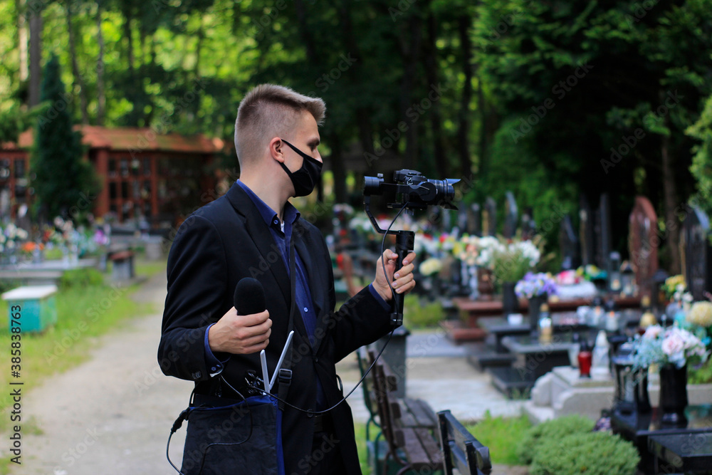 Elegant man in suit is recording grave with cross full of flowers ...