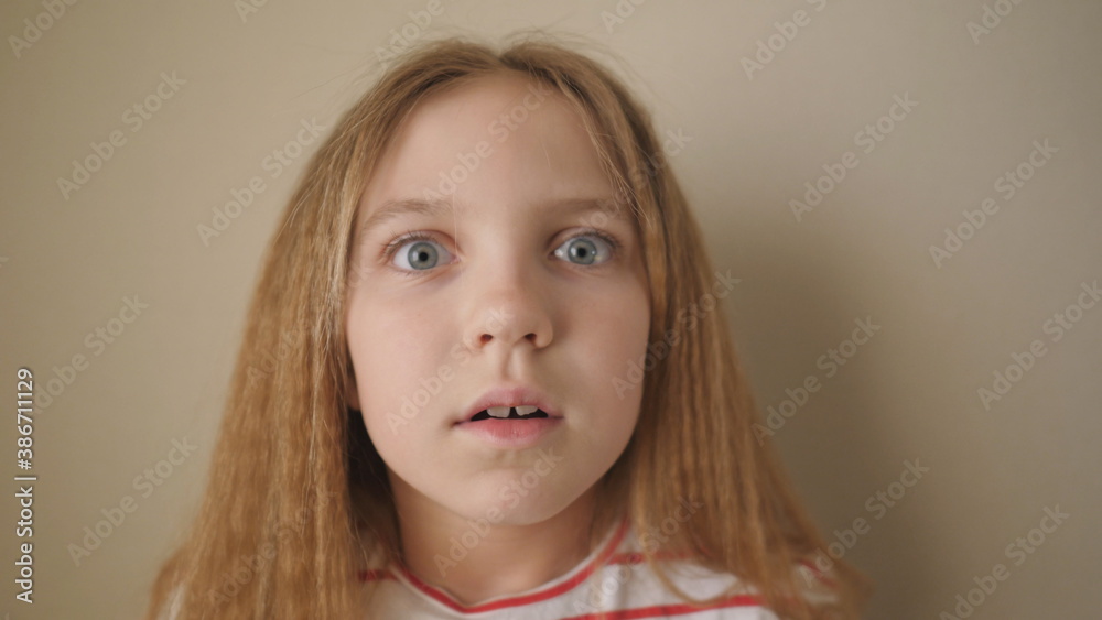Little child with long blonde hair looking into camera with shocked ...