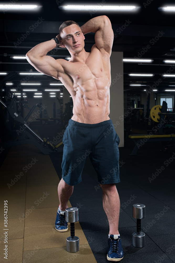 Fotografie A shirtless shredded bodybuilder in shorts is posing full ...
