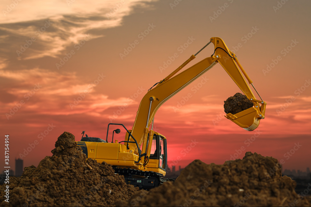 Excavators are digging the soil in the construction site on the sunset ...