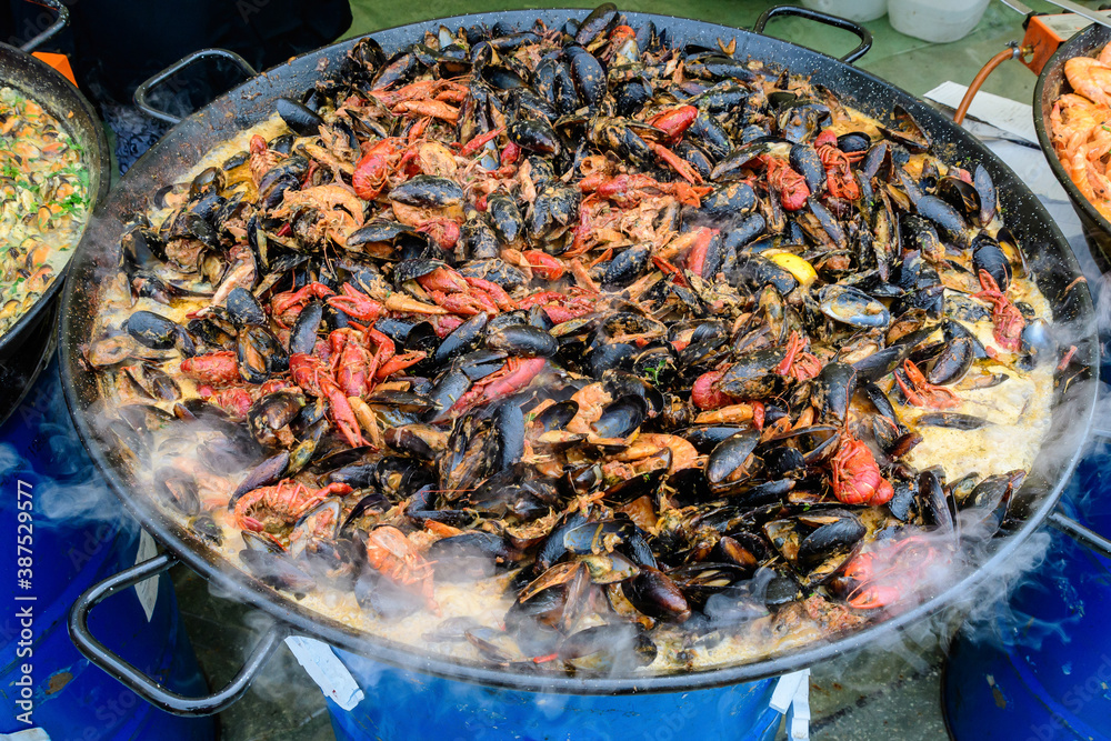 Large group of cooked mussels with tomato and cream sauce at a street ...
