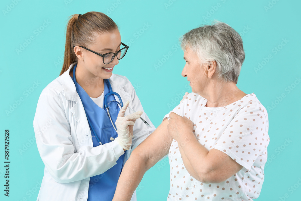 Doctor giving senior diabetic woman insulin injection on color ...