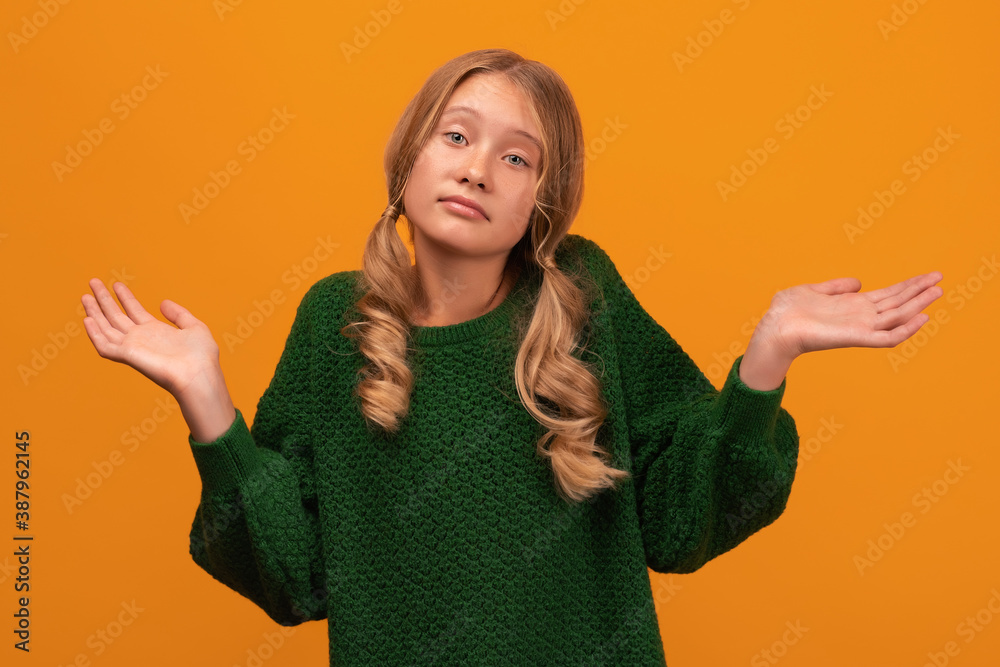 Portrait of pretty blonde teen shrugging with spread palms and saying ...