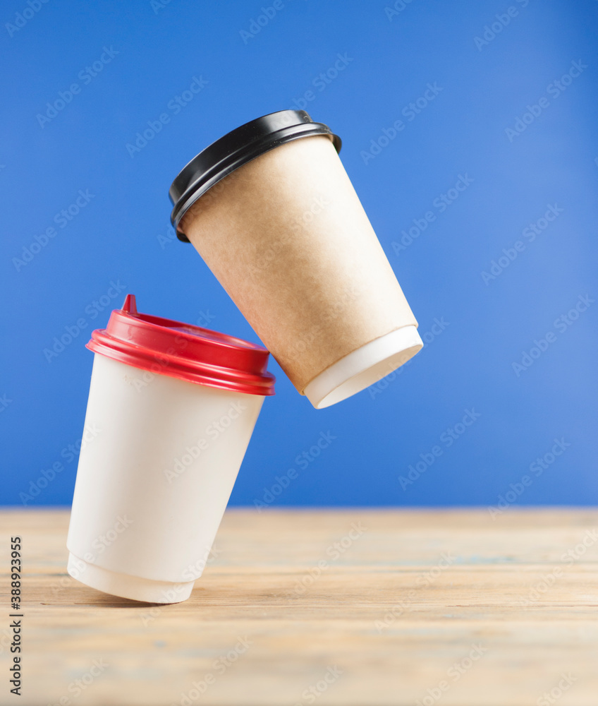 disposable paper flying coffee cups on a blue background hanging on ...