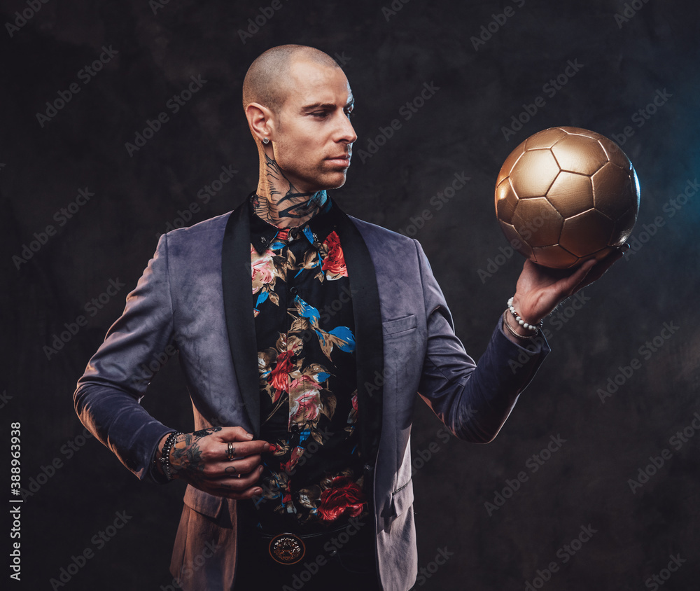 Serious guy in dark custom suit with tattoo and short haircut poses ...