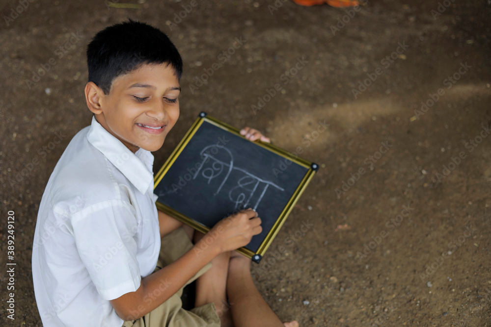 Cute indian child studying at home, writing shiksha word in marathi ...