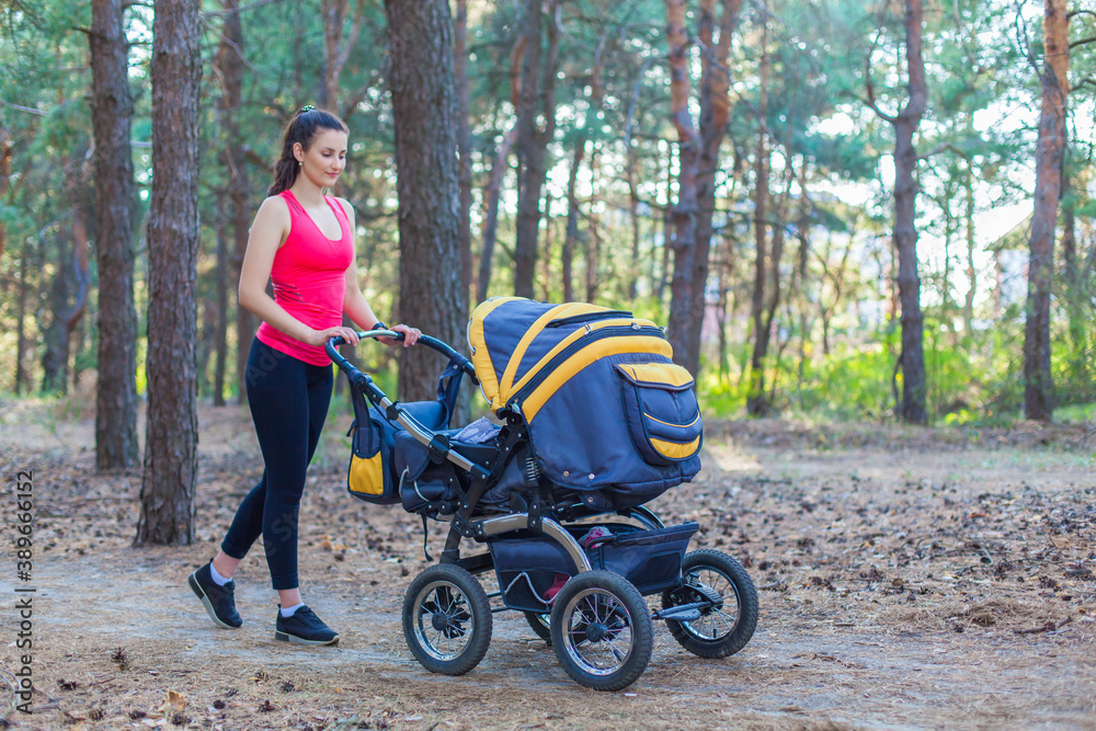 Nature walk with stroller, young active mother in sportswear walking on ...