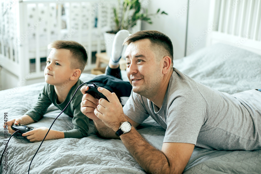 Smiling family son and dad playing video games and having fun together ...