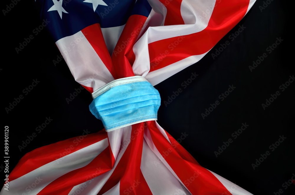 Flag of USA tied with a face protection mask. COVID - 19 problems in ...