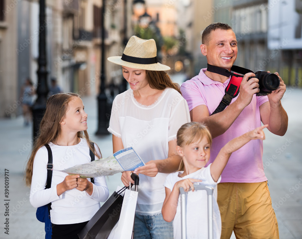 Happy tourist family of four using map and making amateur photo of ...