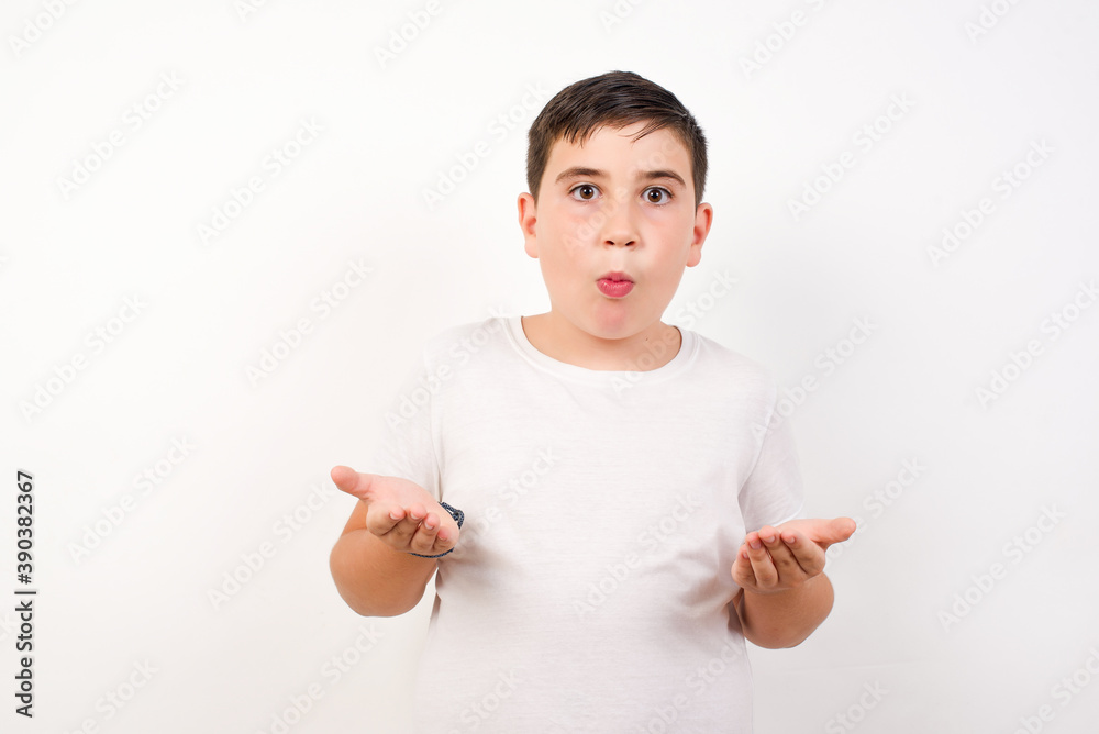 Puzzled and clueless Caucasian young boy standing against white ...