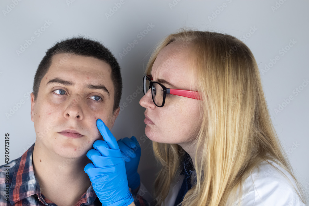 An allergist or dermatologist examines red spots on a man’s face. The ...