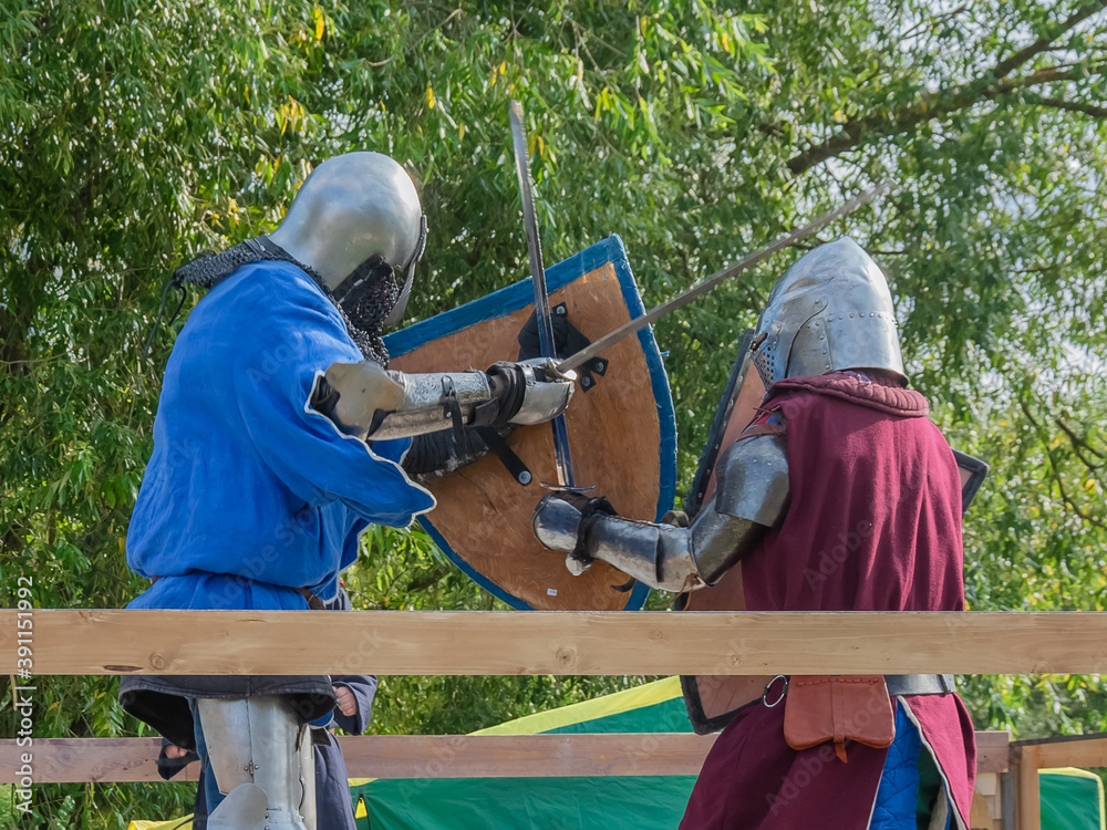 Two foot warriors in heavy medieval armor fight in the arena. Armed ...