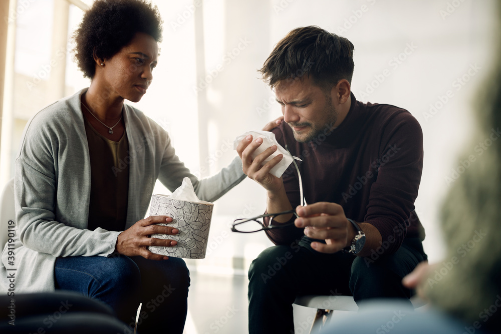 Sad man crying while talking about his issues during group therapy ...