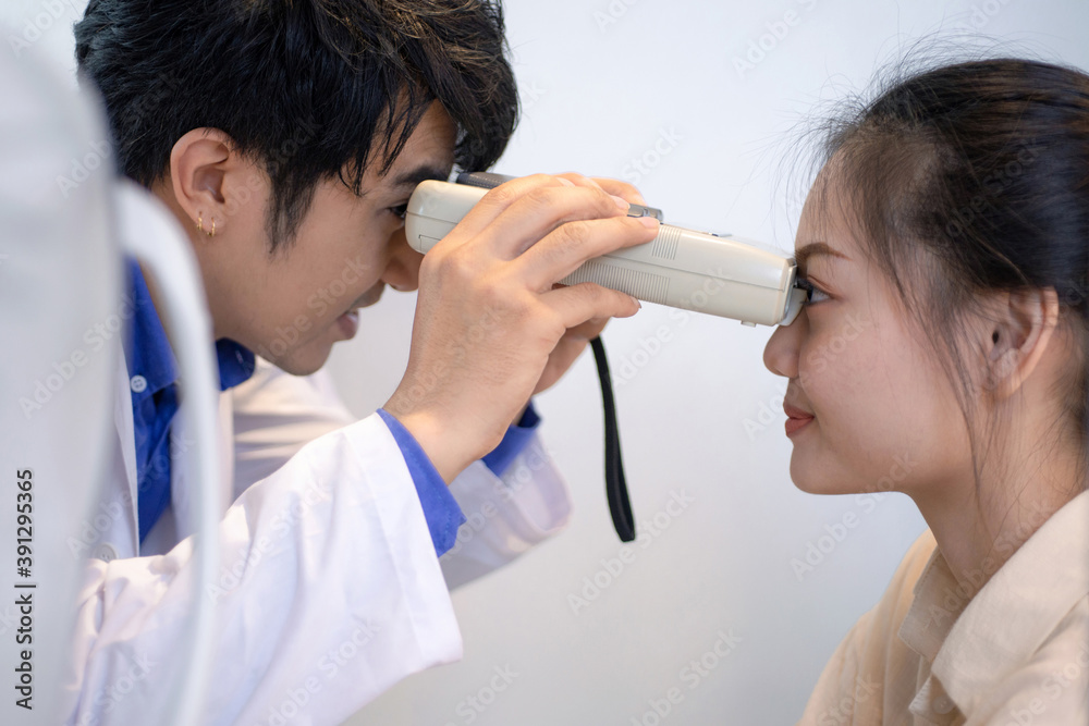 Male optometry specialist performs eye examination of female patients ...