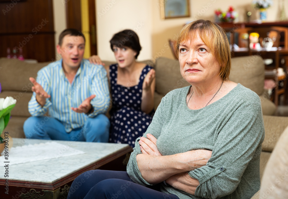 Portrait of upset offended elderly woman sitting on sofa at home on ...